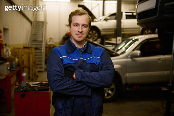 Confident portrait of an auto mechanic dressed in professional uniform ...