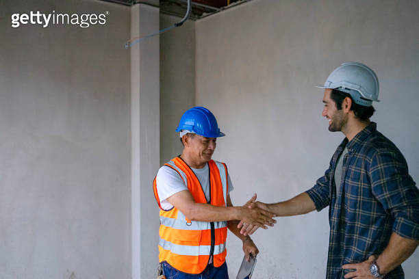 Blue collar workers are working with co worker at construction site ...