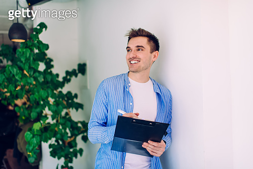 Cheerful Caucasian trainee with paper folder doing test task satisfied ...