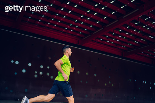 Side view of determined male runner sprinting during cardio training at ...