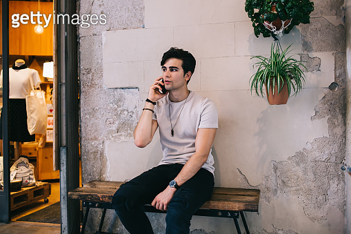 Contemplating stylish Hispanic man talking on smartphone on street 이미지 ...