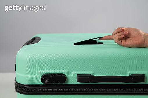 A woman demonstrates a broken suitcase on a white background. Damaged ...