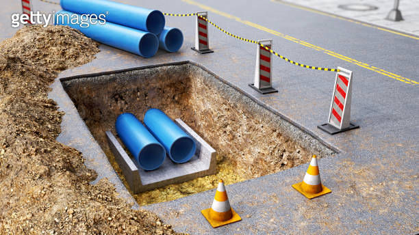 Concept of road works, blue pvc pipes in the digged pit among the road ...