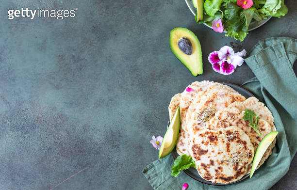 Homemade chapati or roti flatbread with green salad mix, avocado and ...