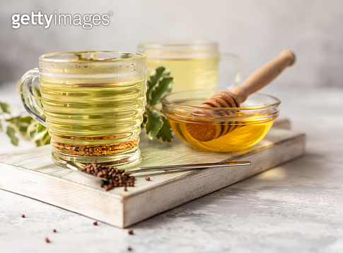 Cup with buckwheat tea, granules and honey, light grey background ...