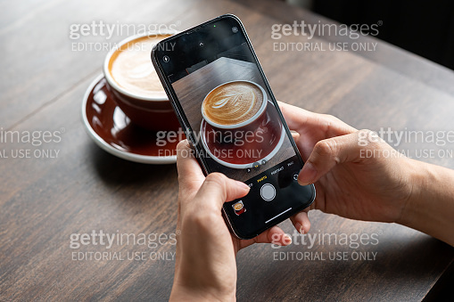 Hands woman using Iphone 13pro taking photo of a cup of latte in cafe ...