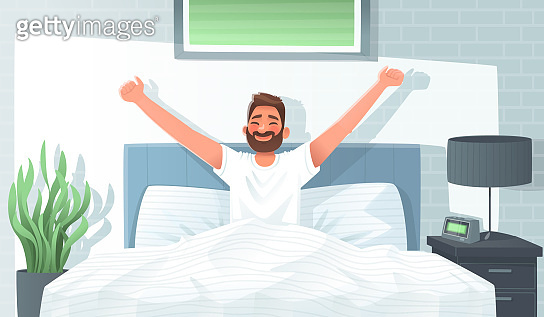 Happy man woke up and stretches in bed. Good morning. Awakening. Wake ...