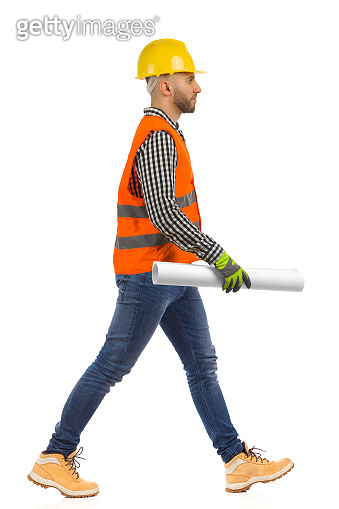 Construction worker is walking with document roll in hand. Side view ...