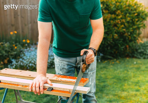 Mid adult man sawing wood using hand saw in garden 이미지 (1393833929 ...