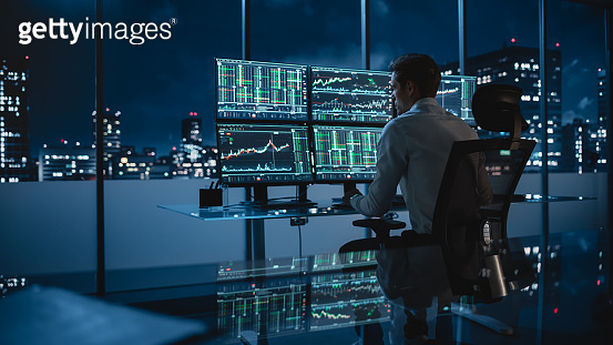 Financial Analyst Working on a Computer with Multi-Monitor Workstation ...