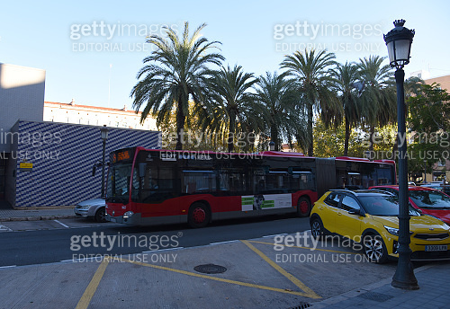 Red city bus travels down a street in city of Valencia. Public ...