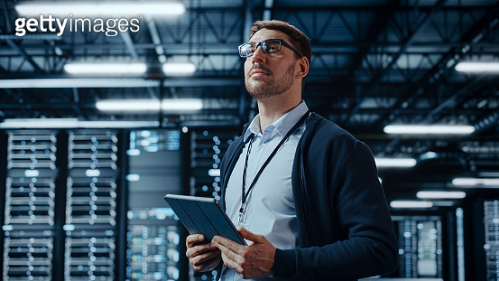 Successful Data Center IT Specialist Using Tablet Computer. Server Farm Cloud Computing Facility ...