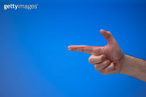 Male hand making a pistol gesture with am elastic rubber band. Close up ...