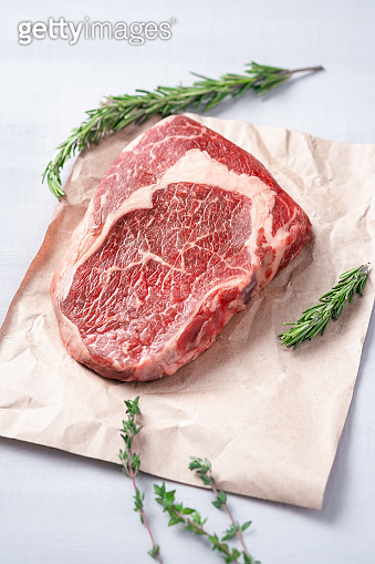 Raw rib eye steak on craft paper with cooking ingredients and spiced ...