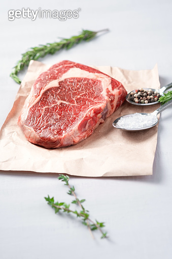 Raw rib eye steak on craft paper with cooking ingredients and spiced ...