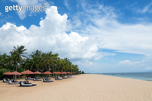 Empty beach with umbrellas and deck chairs. Palm trees. Beautiful ...