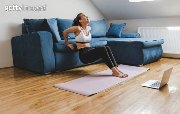 Young adult woman doing workout exercise at home using home furniture ...