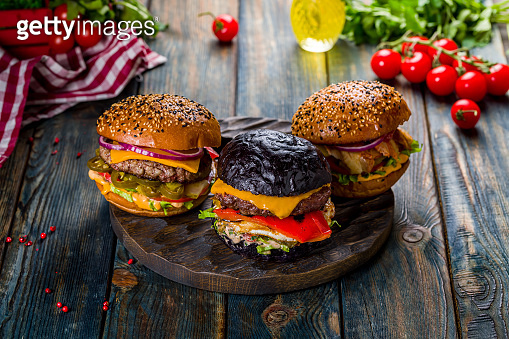 Three burgers, Burger with meat patty, onion rings jalapeno, on board ...