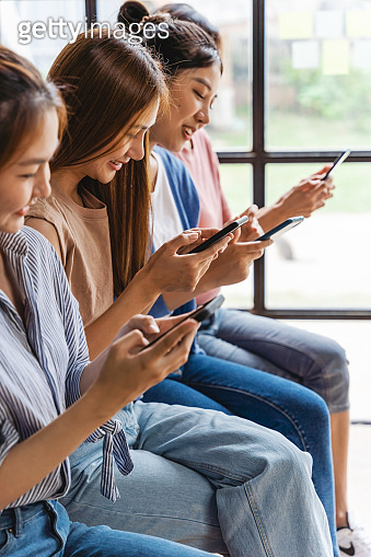 Group of four young Asian female people using smartphones together ...