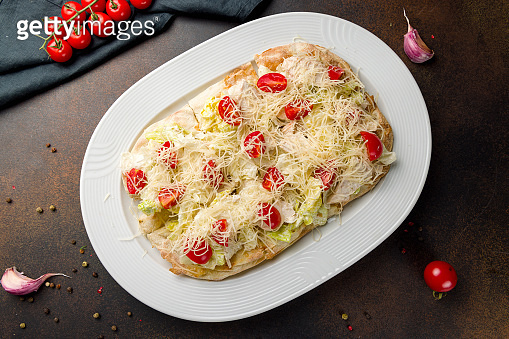 Roman pizza, Pinsa caesar with chicken and salad on roman dough on dark ...