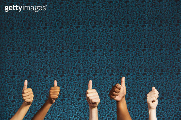 Diverse group of hands giving the thumbs-up sign in front of an ornate ...