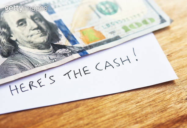 Here's the cash! says handwritten note under a US hundred-dollar ...