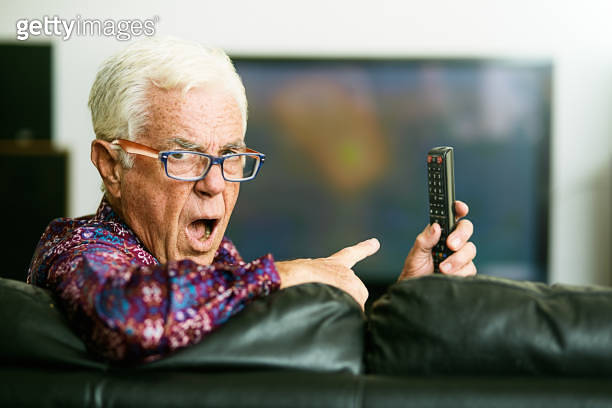 Technology trouble: Confused elderly man having difficulty with his TV ...