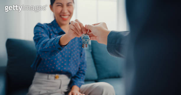 Close up of Asian woman sign contract getting keys on sofa in living ...