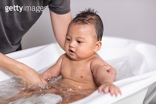 Calm of asian newborn baby bathing in bathtub.mother bathing her son in ...