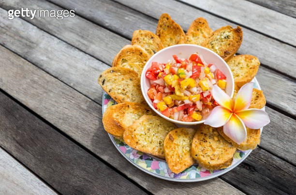 Homemade mango salsa with garlic bread with space on wooden table ...