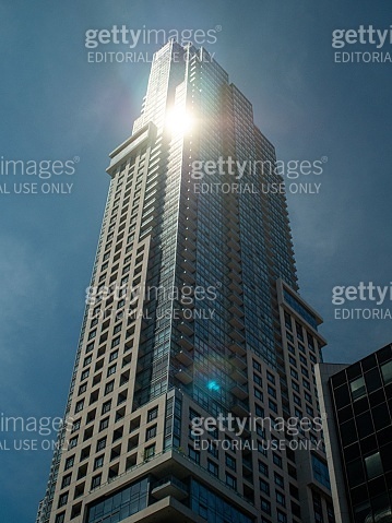 Vertical shot of a skyscraper with a flare on windows against a blue ...