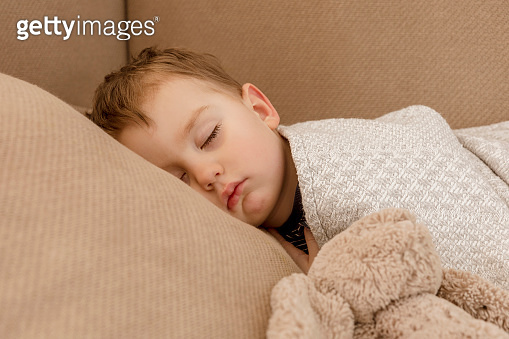 Little, cute caucasian boy sleeping on couch at home. Child taking day ...