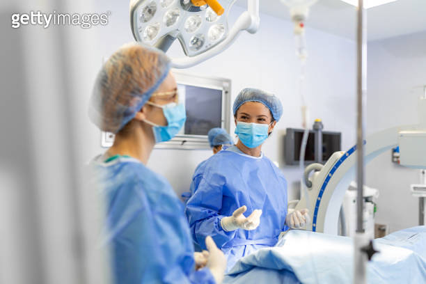 Female surgeon with surgical mask at operating room. Young woman doctor ...