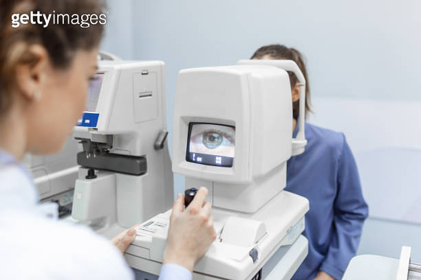 Doctor testing for eyes with special optical apparatus in modern clinic ...