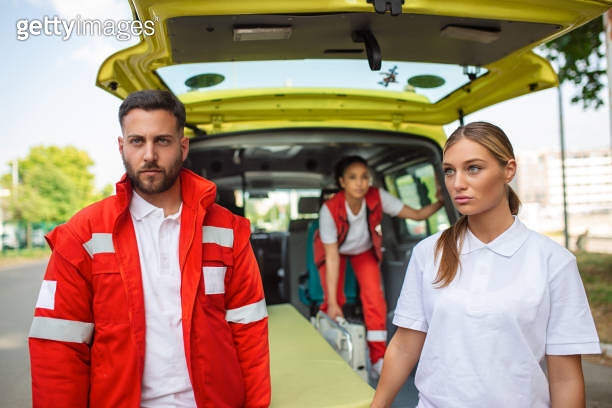 young paramedics moving ambulance stretcher from car. Paramedics in ...