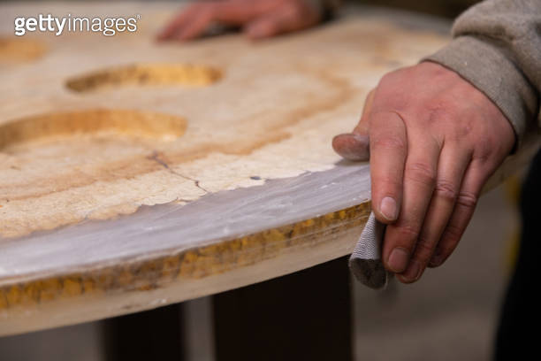 Closeup of person sanding wooden table using sandpaper in workshop 이미지 ...
