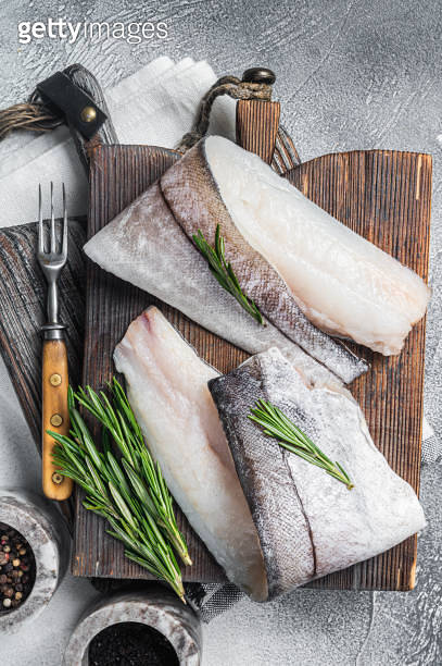 Haddock fish fillet, raw seafood meat on wooden board with herbs. White ...
