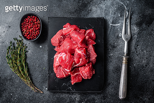 Raw diced red beef meat for Goulash on marble board. Black background ...
