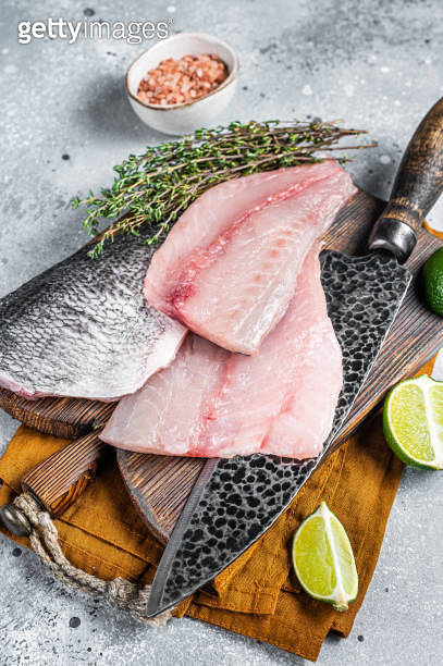 Raw Gilthead Sea bream fish fillets on a butcher cutting board. Gray ...