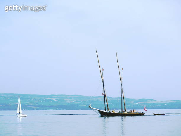Ancient boat on lake of Geneva, Switzerland, with little hill behind ...