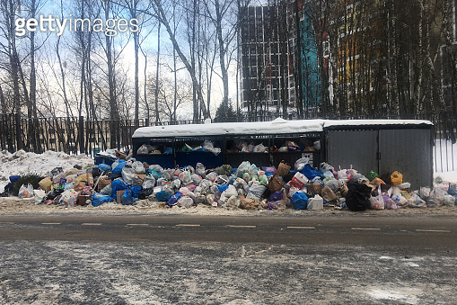 Garbage cans near littered with household garbage in plastic bags ...