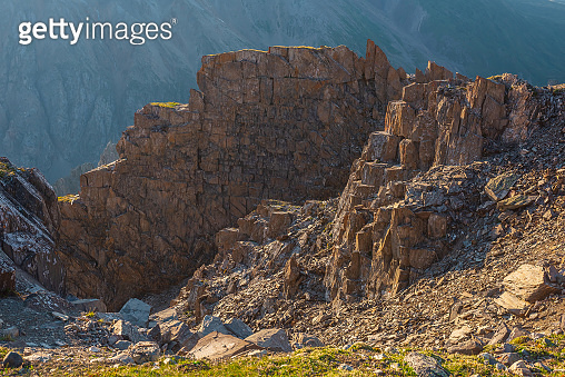 Scenic alpine landscape with mountain wall and sharp stones in sunlight ...