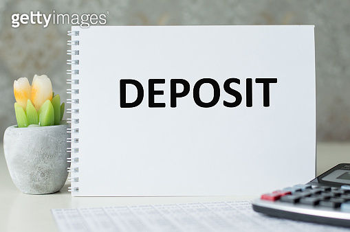 Deposit text on a notepad on the table next to the calculator and a ...