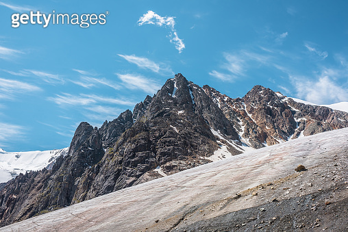 Scenic mountain landscape with glacier under sharp rocks in sunlight ...