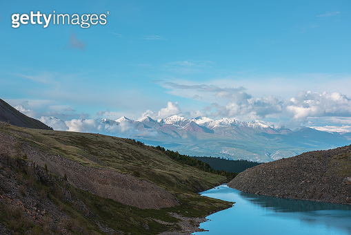 Atmospheric landscape with azure mountain lake against high snow-white ...