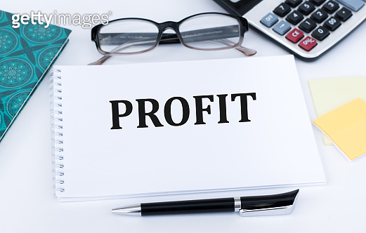 PROFIT text on a notebook on the table next to a pen, glasses, tracing ...