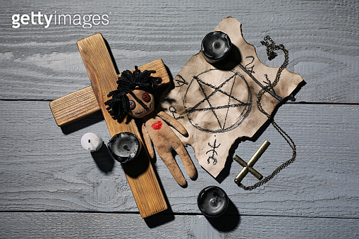 Female voodoo doll with heart and ceremonial items on grey wooden table ...
