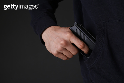 Man hiding gun in pocket against dark background, closeup 이미지 ...