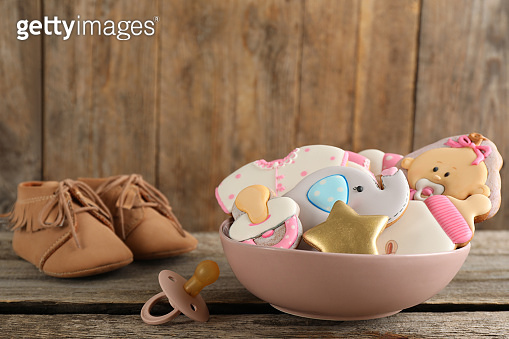 Cute tasty cookies of different shapes, pacifier and booties on wooden ...