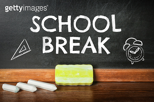 Text School Break and drawings on black chalkboard near table. Seasonal ...